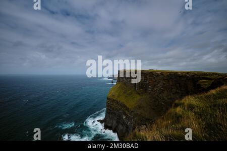 A scenic view of the evergreen Cliffs of Moher in Ireland on a gloomy ...