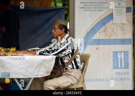 An indigenous Bajau man selling food at the Sunday market (tamu) in ...