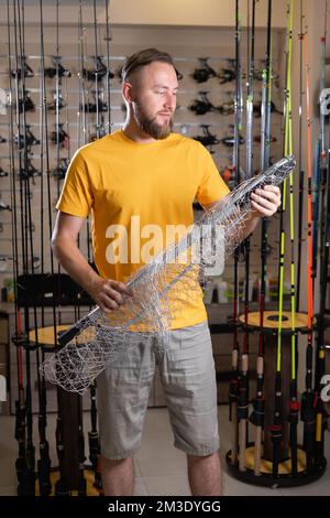 Man chooses fishing rod and landing net in the sports shop Stock Photo ...