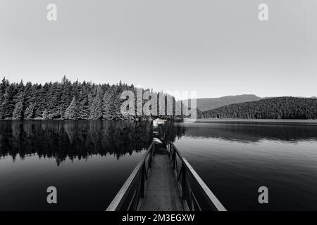 A mesmerizing shot of a wooden dock in a calm sea, with beautiful ...