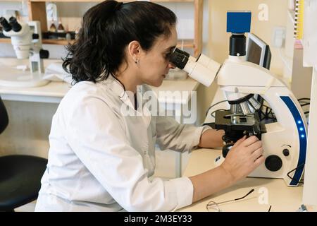 Scientist analyzing microscope slide at laboratory. Young woman ...