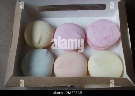 Six colorful handmade marshmallows in a cardboard box on the table ...