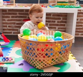 Adorable caucasian baby sucking ball sitting on highchair at home Stock ...
