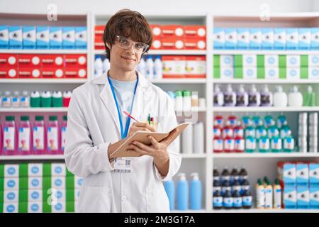 Young blond man pharmacist writing on notebook at pharmacy Stock Photo ...