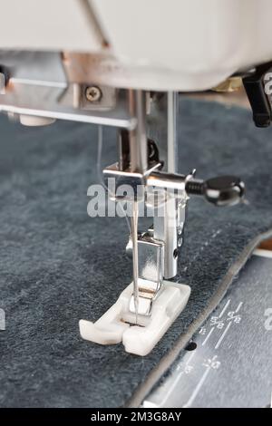 sewing machine with special presser foot makes a seam on grey leather ...