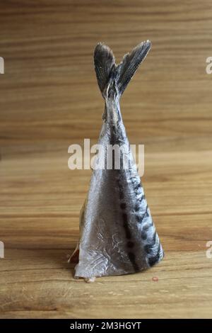 the tail of mackerel fish lies on a wooden surface. Home cooking ...