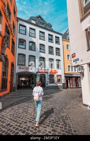 Germany, Cologne, portrait of happy young woman eating jelly on meadow ...