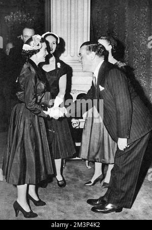 Norman Hartnell, the Royal fashion designer, explains a point to ...
