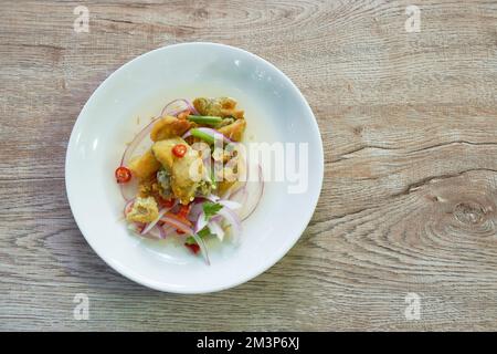deep fried slice snake skin gourami spicy and sour Thai salad on dish ...