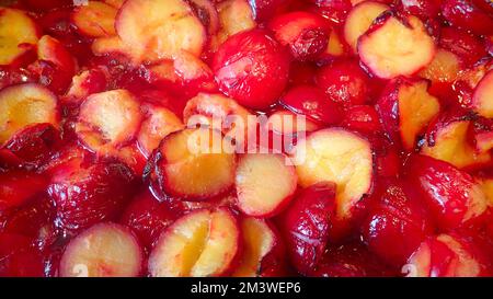 Halved and roasted yellow fleshed red plums gently boiling in a large ...