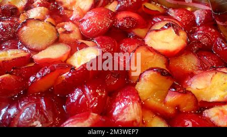 Halved and roasted yellow fleshed red plums gently boiling in a large ...