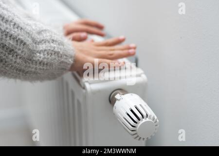 The child's hands warm their hands near the heating radiator. Saving ...