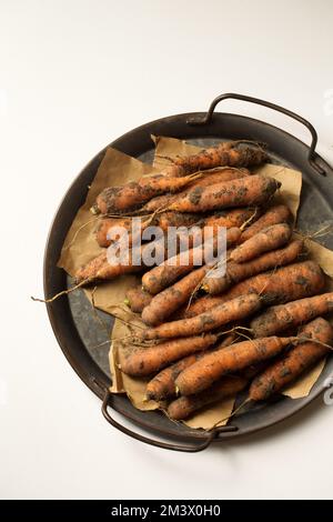 Fresh unwashed carrots in a square basket on a white background Stock ...