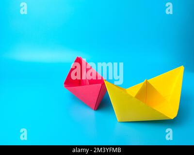 A big red paper ship and smaller yellow ones on turquoise background ...