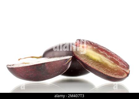 Two halves and one whole berry of black grapes, close-up, isolated on ...