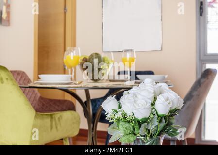 A bouquet of white artificial roses decorating a room with a table full ...