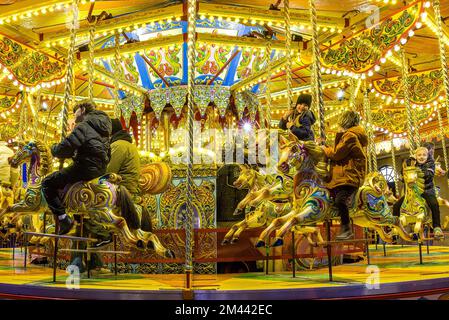 Brightly coloured fairground carousel with galloping ponies. At ...