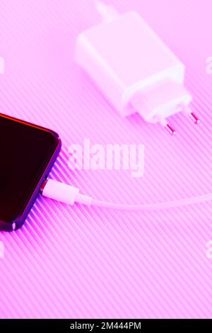 Smartphone charging on a purple background. Mobile phone with connected ...