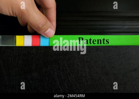 Hand picking patents file record in black binder folder. Patent and ...