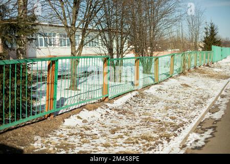 Fence around school in winter. Green fence in city. Private territory ...