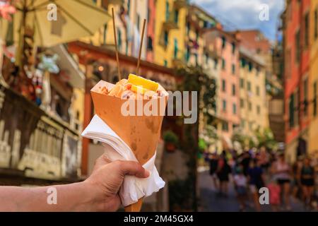 Hand holding a cone of fritto misto, Italian street food mix of fried ...