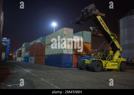 Reach Stacker during operation. Reach-stacker container loader during night work. Industrial ...