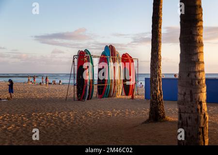 Surf boards stacked into racks on Waikiki Beach in the evening light ...