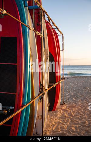 Surf boards stacked into racks on Waikiki Beach in the evening light ...