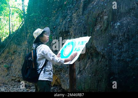 Female geologist using a map, examining a natural path and analyzing ...