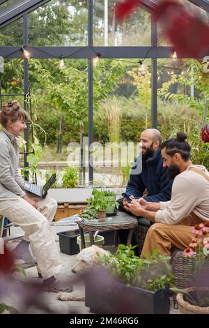 Smiling friends talking in greenhouse Stock Photo - Alamy
