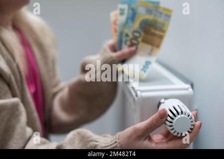 Person holding euro banknotes near heater Stock Photo - Alamy