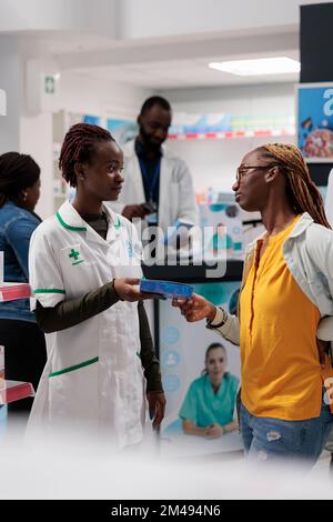 African american woman pharmacist talking on smartphone reading ...