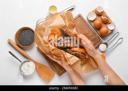 Female hands with tasty poppy seed bun on white background, closeup ...