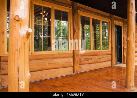 Rustic log home facade with panoramic glass pane windows and veranda ...