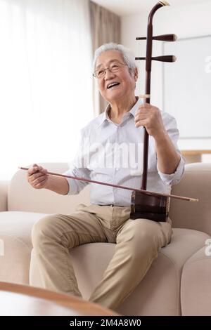 Senior Chinese man playing traditional musical instrument Erhu Stock ...