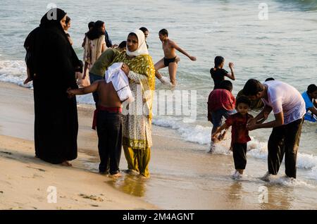Indian tourists having a swim, wearing all their cloths, in the ocean ...