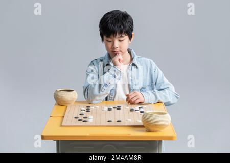 Cute Chinese boy playing the game of Go Stock Photo - Alamy