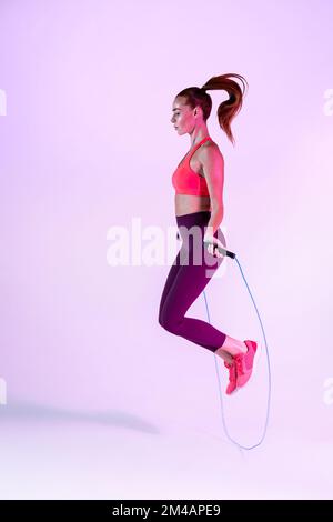 Fit female athlete with ponytail jumping with rope during fitness ...