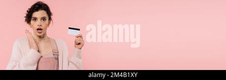 Amazed woman in warm clothes pointing with finger isolated on blue ...