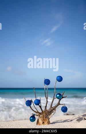 Dead corals decorated with blue Christmas balls standing on the sand ...