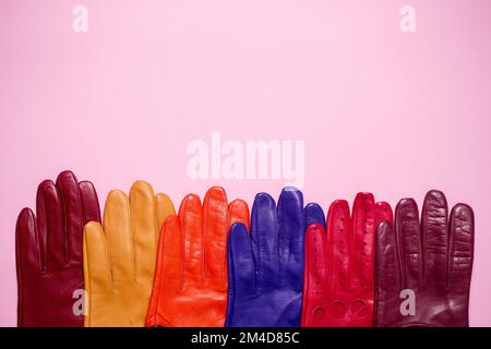 Many bright multi-colored gloves on a pink background Stock Photo - Alamy