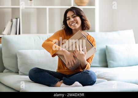 Smiling female courier holding present box and megaphone in hands ...