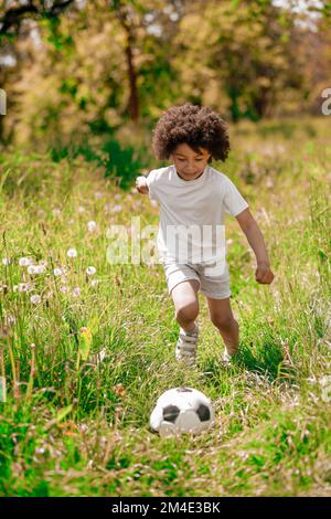 Curly-haired boy in white sportswear with a football Stock Photo - Alamy