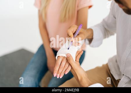Woman in a plaster cast writing in notebook lying on a couch in the ...