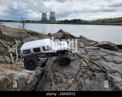 A toy car Jeep Wrangler on stones by the lake with a view of nuclear ...