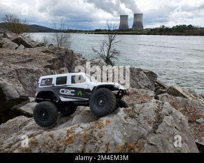 A toy car Jeep Wrangler on stones by the lake with a view of nuclear ...