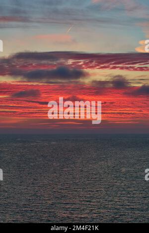 A vertical shot of a gorgeous red sunset reflected on the sea with a ...