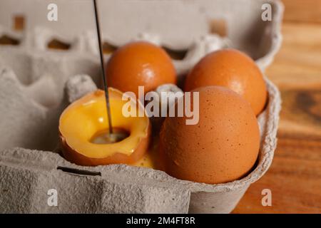 Woman beating an egg in its own shell with a small blender, several ...