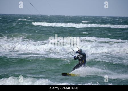 Kitesurfing, riding board waves during storm holding to flying kite ...