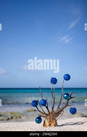 Dead corals decorated with blue Christmas balls standing on the sand ...